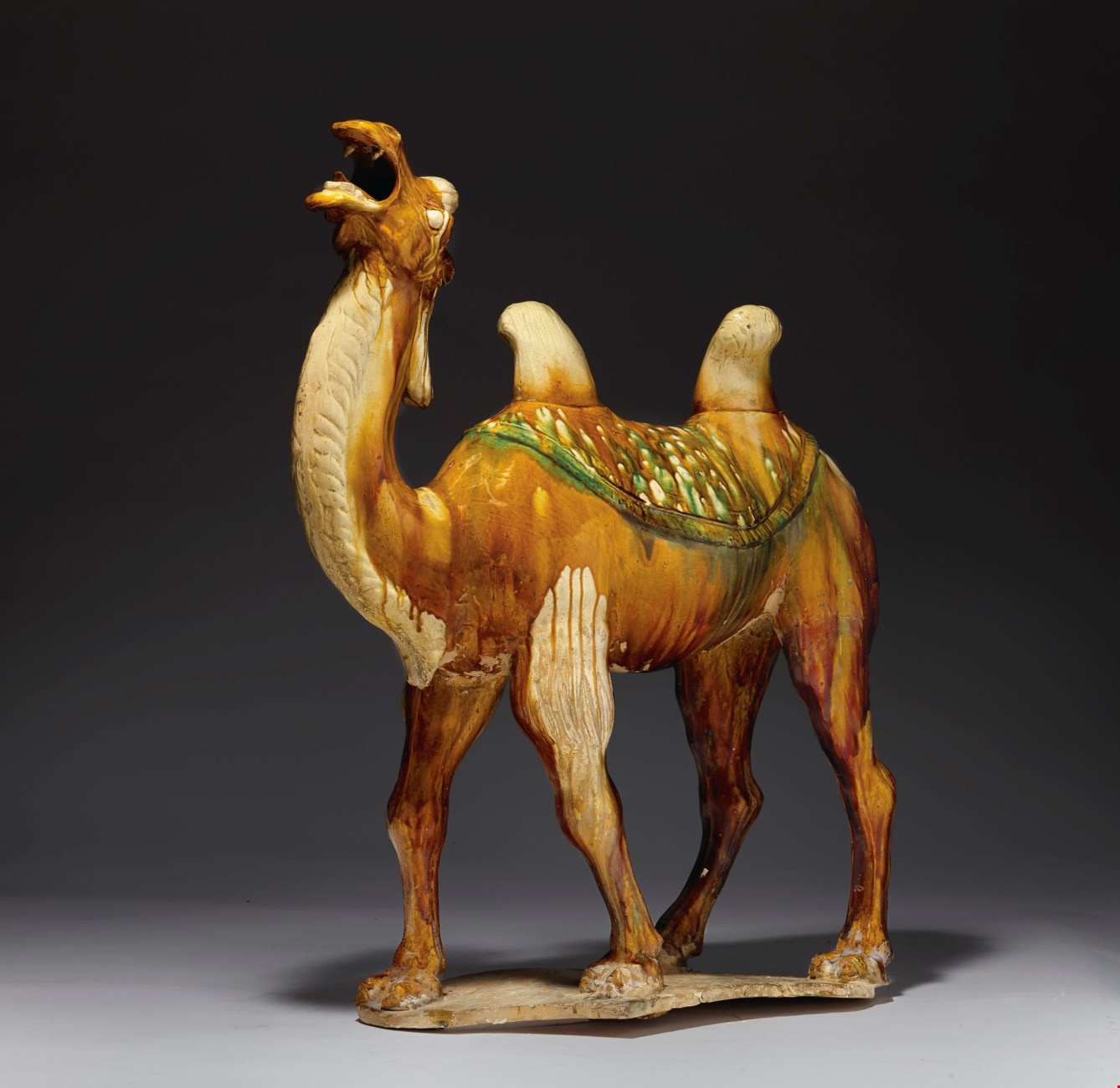 A LARGE SANCAI-GLAZED POTTERY FIGURE OF A STRIDING BACTRIAN CAMEL, TANG ...